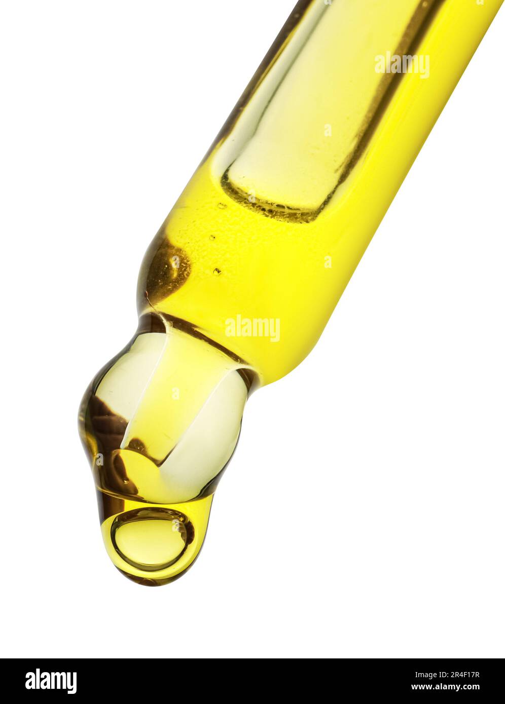Dripping yellow facial serum from pipette on white background, closeup ...
