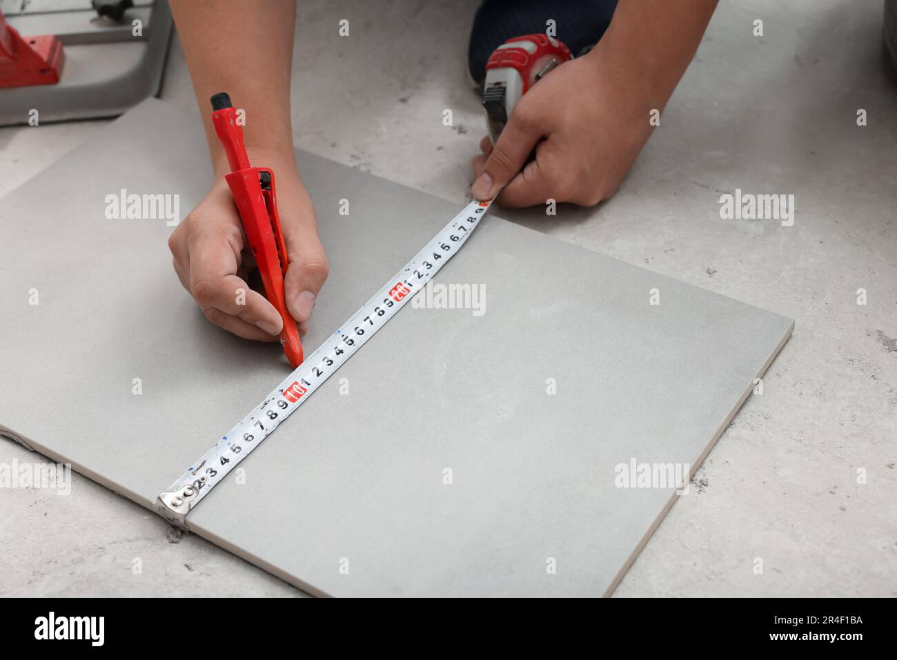 Worker measuring and marking ceramic tile on floor, closeup Stock Photo ...