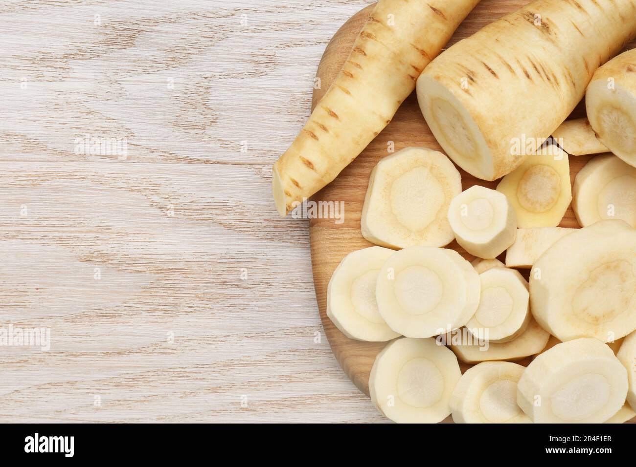 Whole and cut fresh ripe parsnips on white wooden table, top view ...