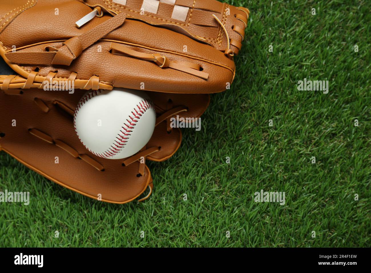 Catcher's mitt and baseball ball on green grass, top view with space ...