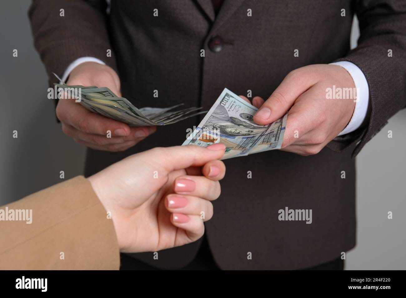 Man giving money to woman on light grey background, closeup. Currency ...
