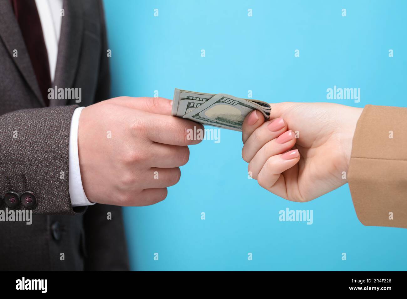 Man giving money to woman on light blue background, closeup. Currency ...