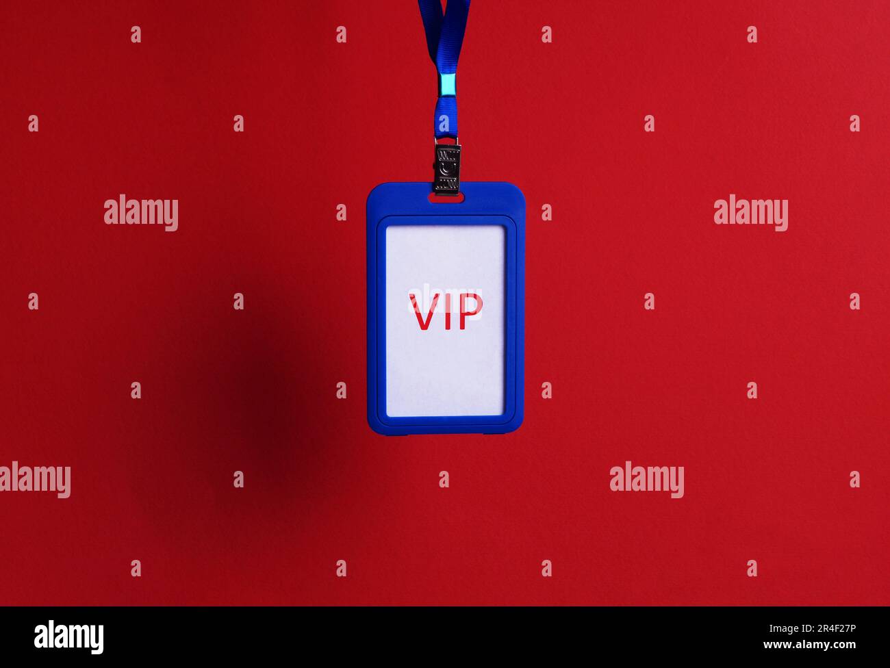 Blue plastic vip badge hanging on red background Stock Photo - Alamy