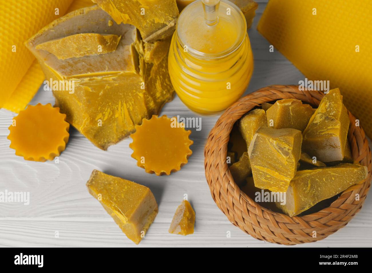 Different natural beeswax blocks and jar of honey on white wooden table ...