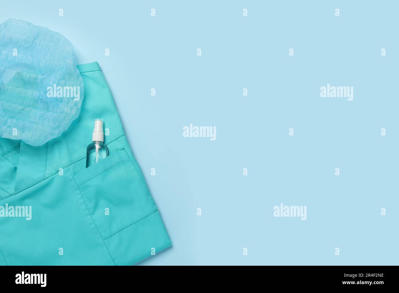 Medical uniform, cap and antiseptic on light blue background, flat lay ...
