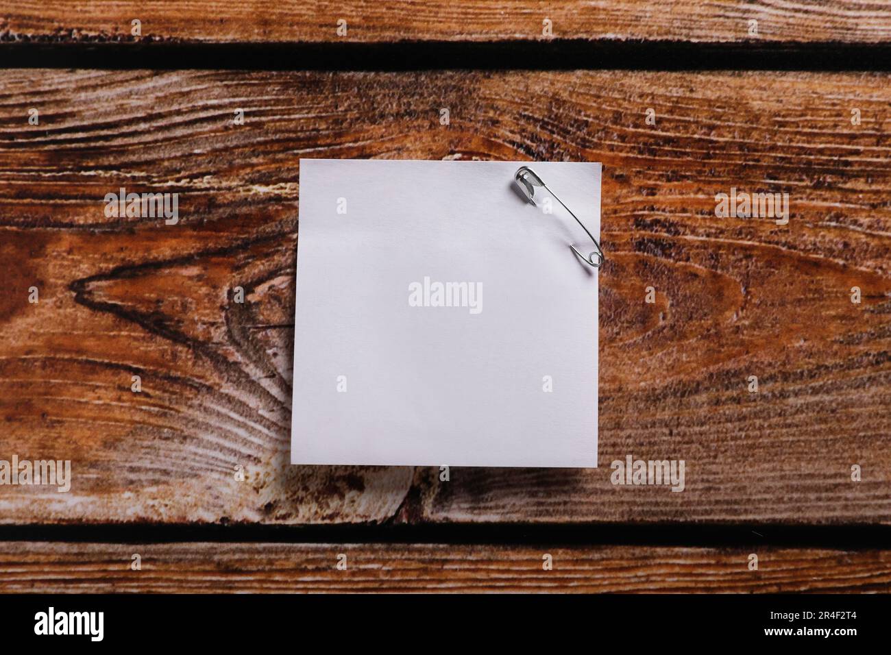 Paper sheet attached with safety pin on wooden table, top view. Space ...