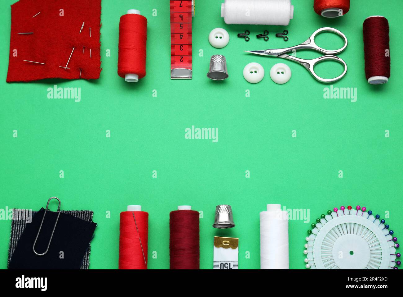 Flat lay composition with thimbles and different sewing tools on green ...