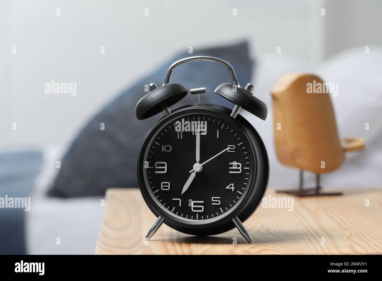 Black alarm clock on wooden nightstand in bedroom Stock Photo - Alamy
