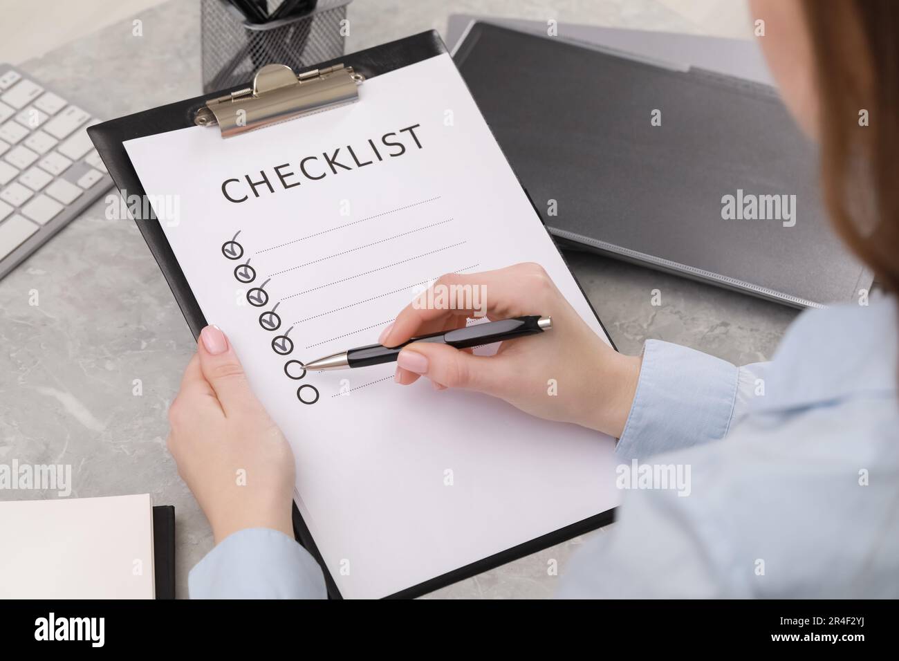 Woman filling Checklist at grey marble table, closeup Stock Photo - Alamy