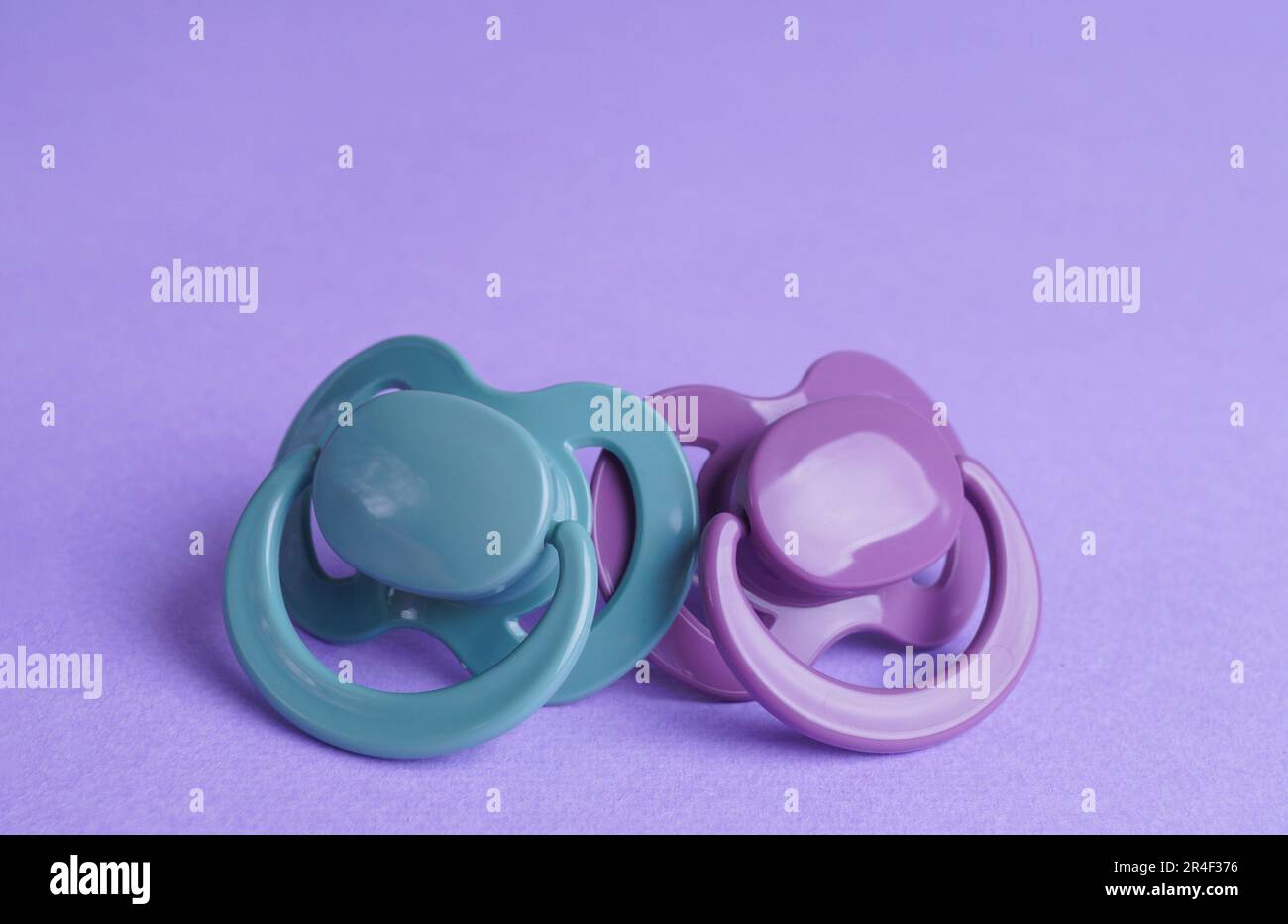 New baby pacifiers on purple background, closeup Stock Photo - Alamy