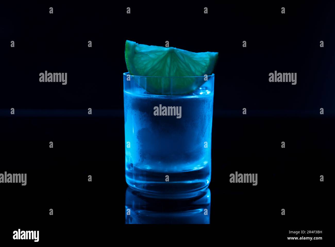 Shot glass of vodka with lime slice on dark background Stock Photo - Alamy