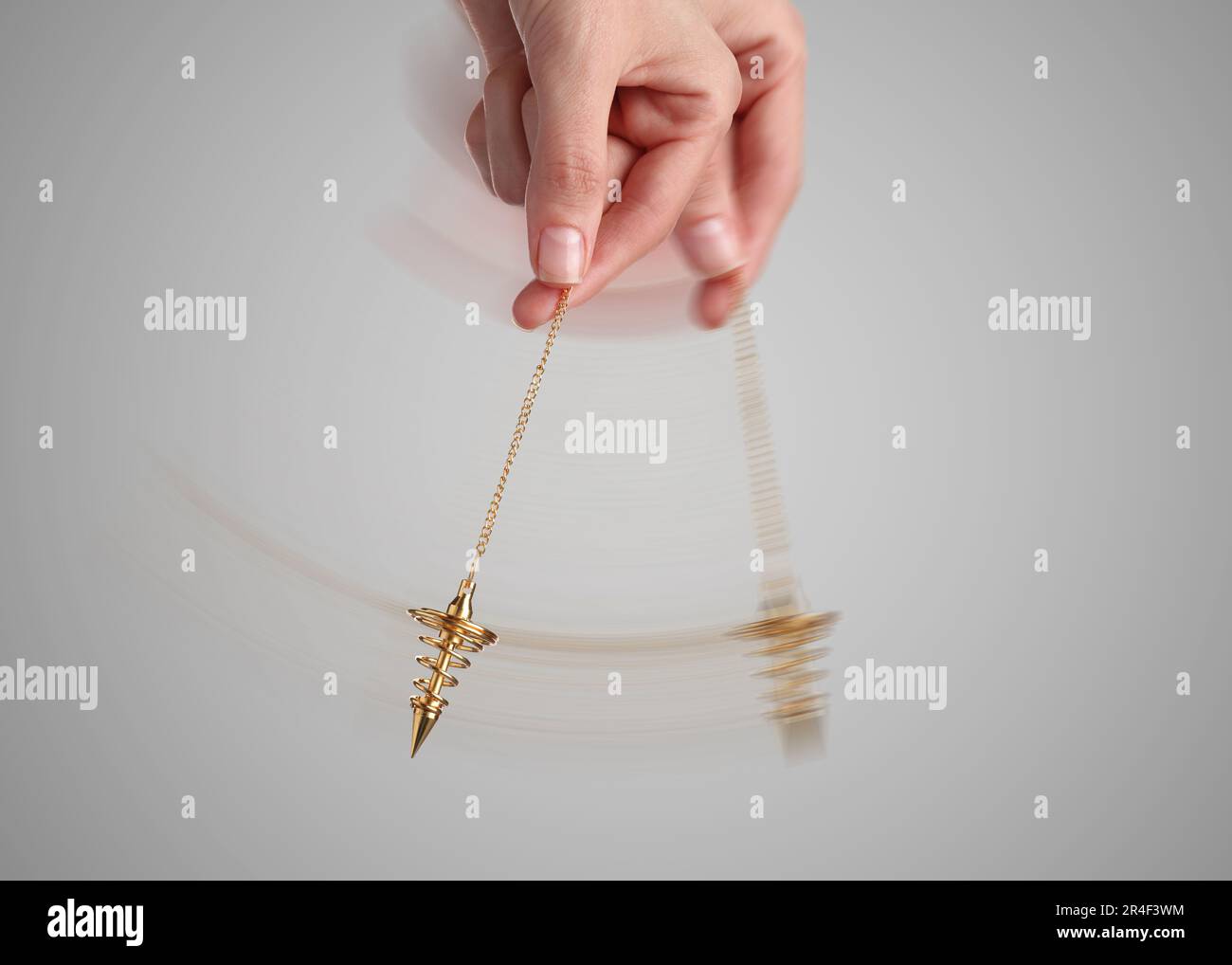 Hypnosis session. Woman swinging pendant on light background, closeup ...