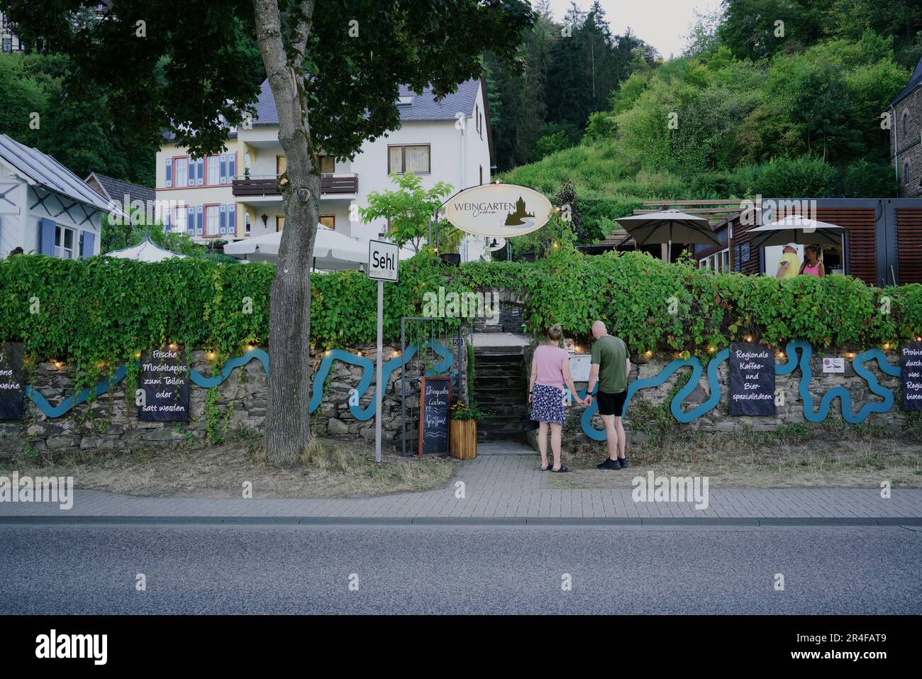 Man and Woman check out a menu posted on a stone wall at an outdoor ...