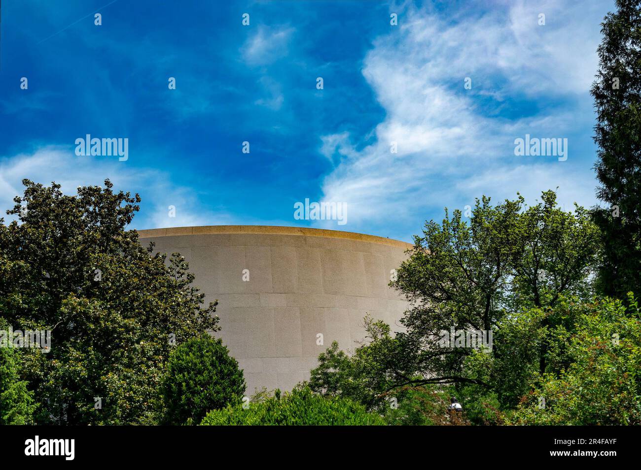 A round concrete building behind trees Stock Photo - Alamy