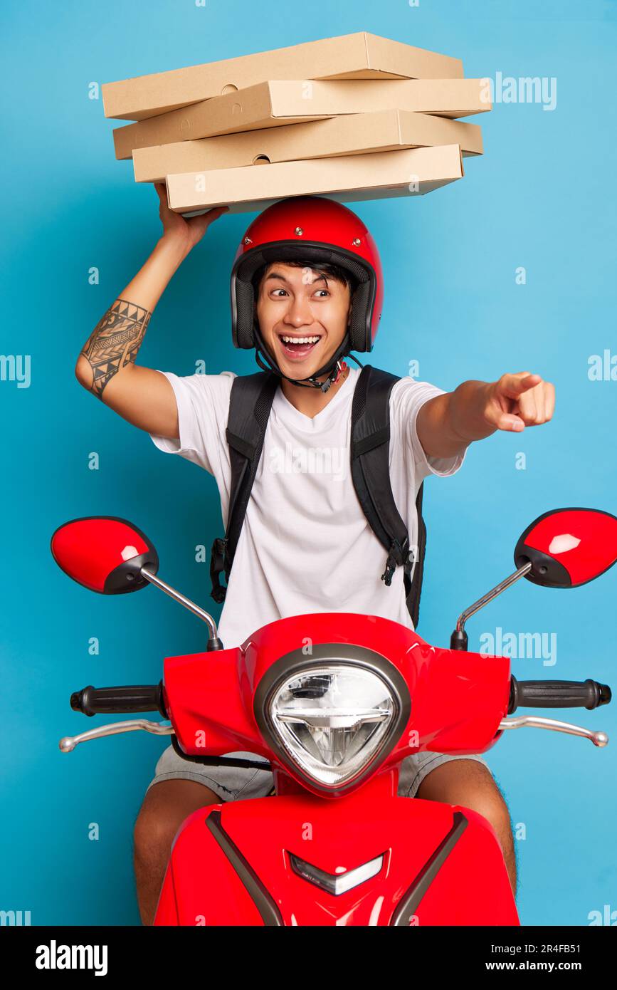 Young smiling delivery guy in white t-shirt and red helmet sits on red ...