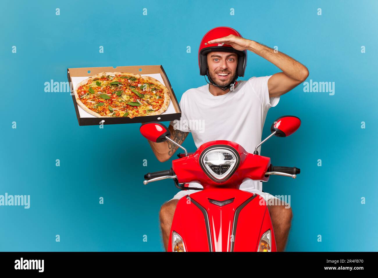 Cute bearded man rides red scooter holding pizza box in one hand ...