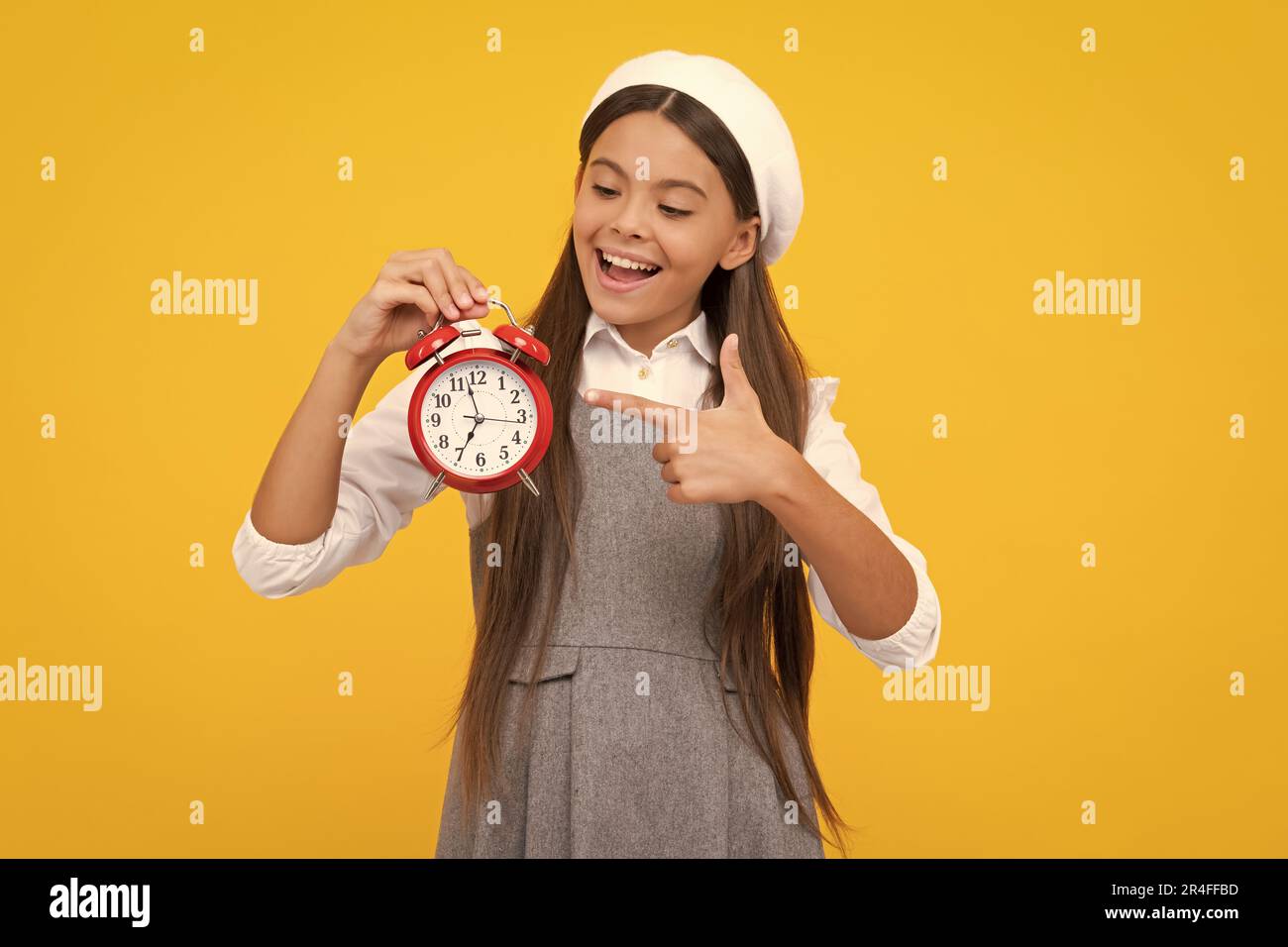 Teen student girl hold clock isolated on yellow background. Time to ...