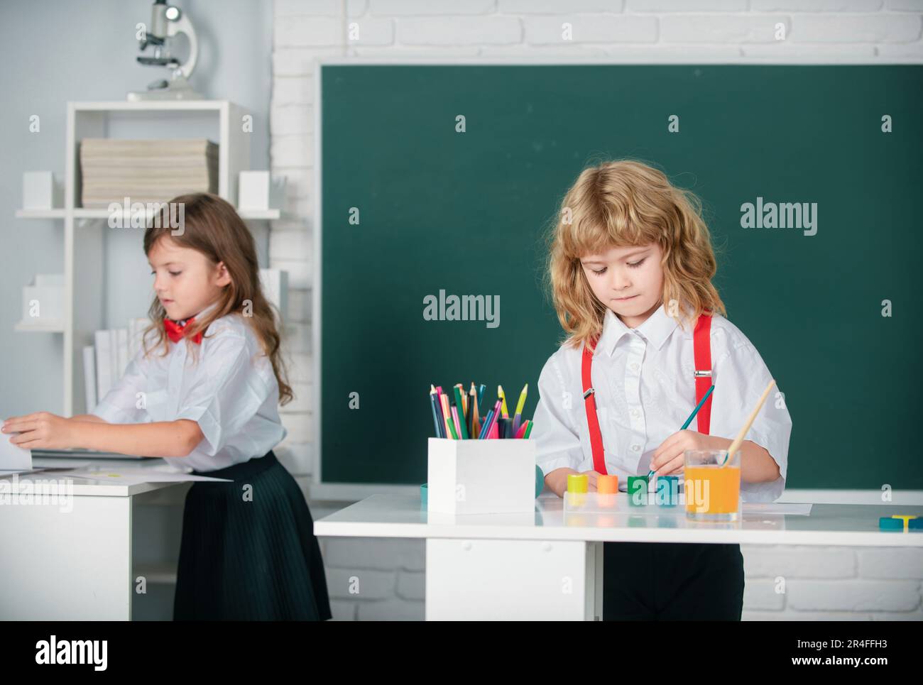 School children drawing a colorful pictures with pencil crayons in ...
