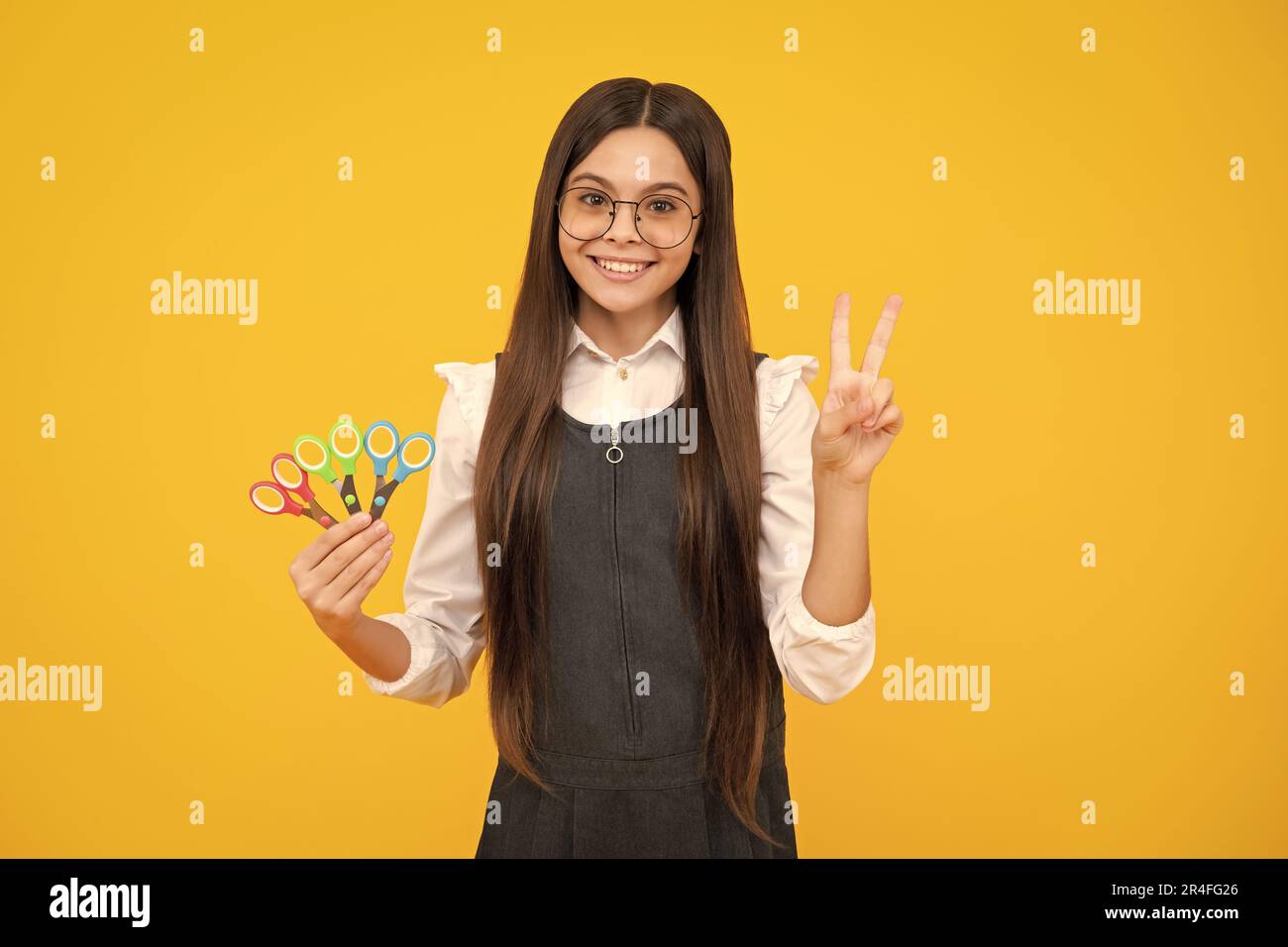 Teenage girl with scissors, isolated on yellow background. Child ...