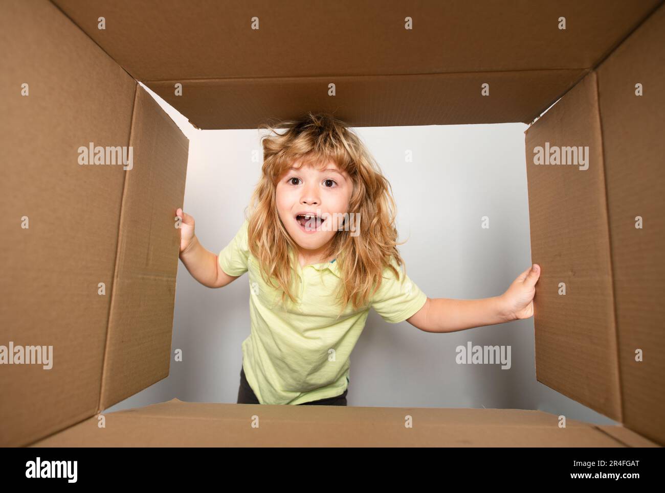 Child boy opening a carton box and looking inside, unpacking concept ...