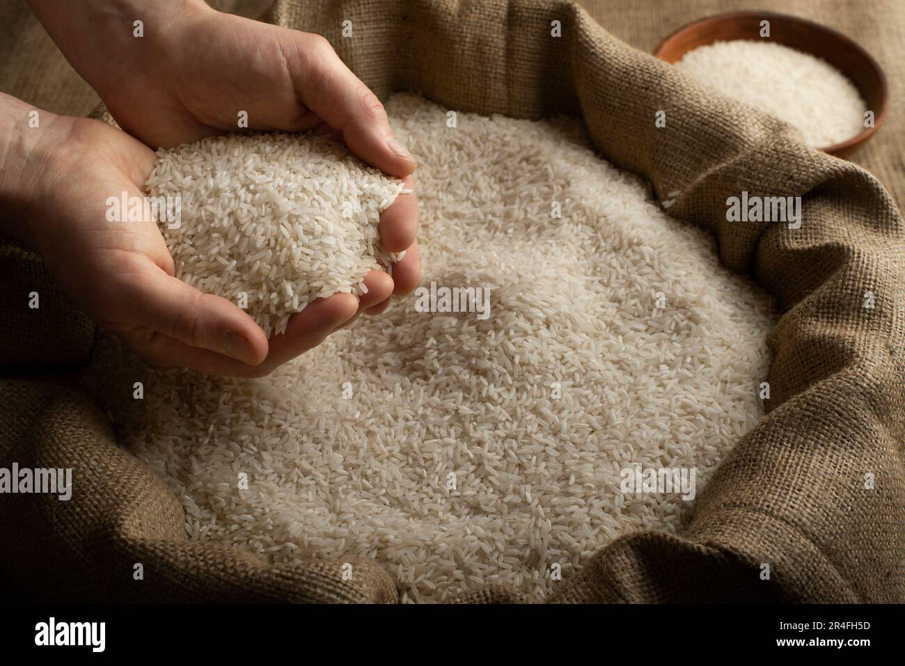Human hands holding handful of rice over burlap sack Stock Photo - Alamy