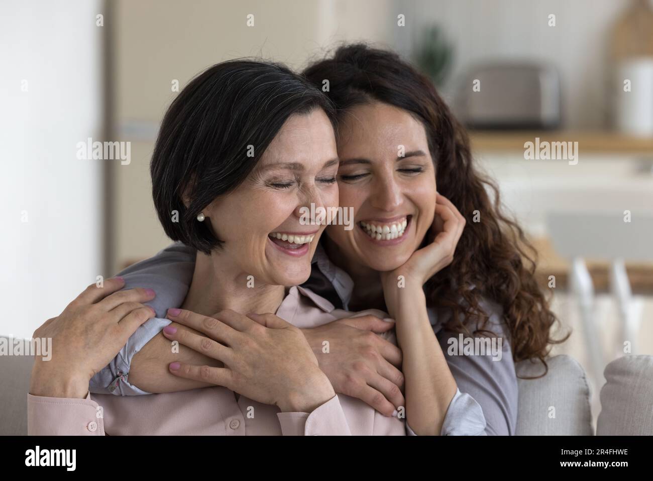 Happy positive mature mother and adult kid woman hugging, cuddling ...