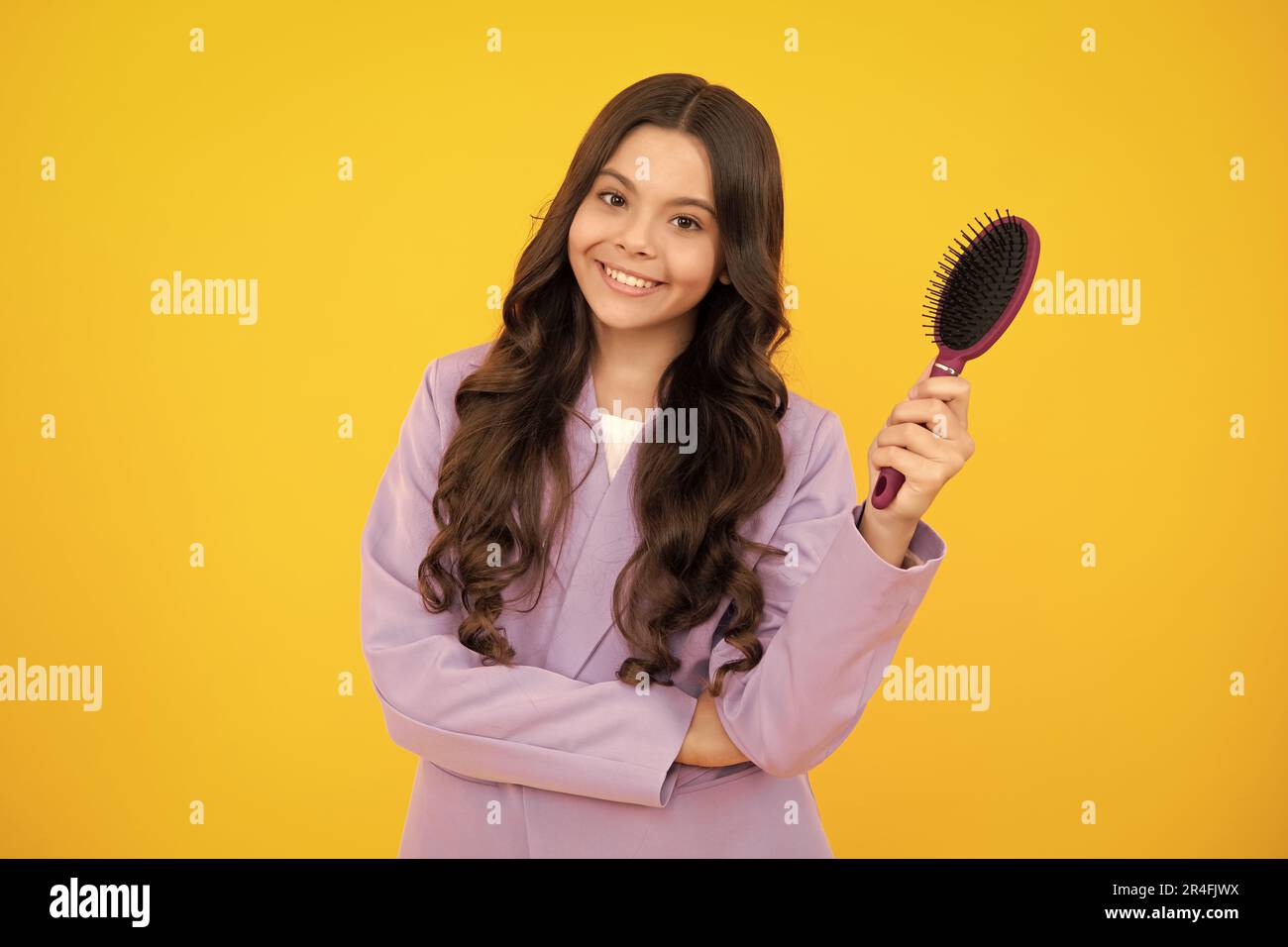 Teenager brushing combing hair with big comb on yellow isolated studio ...