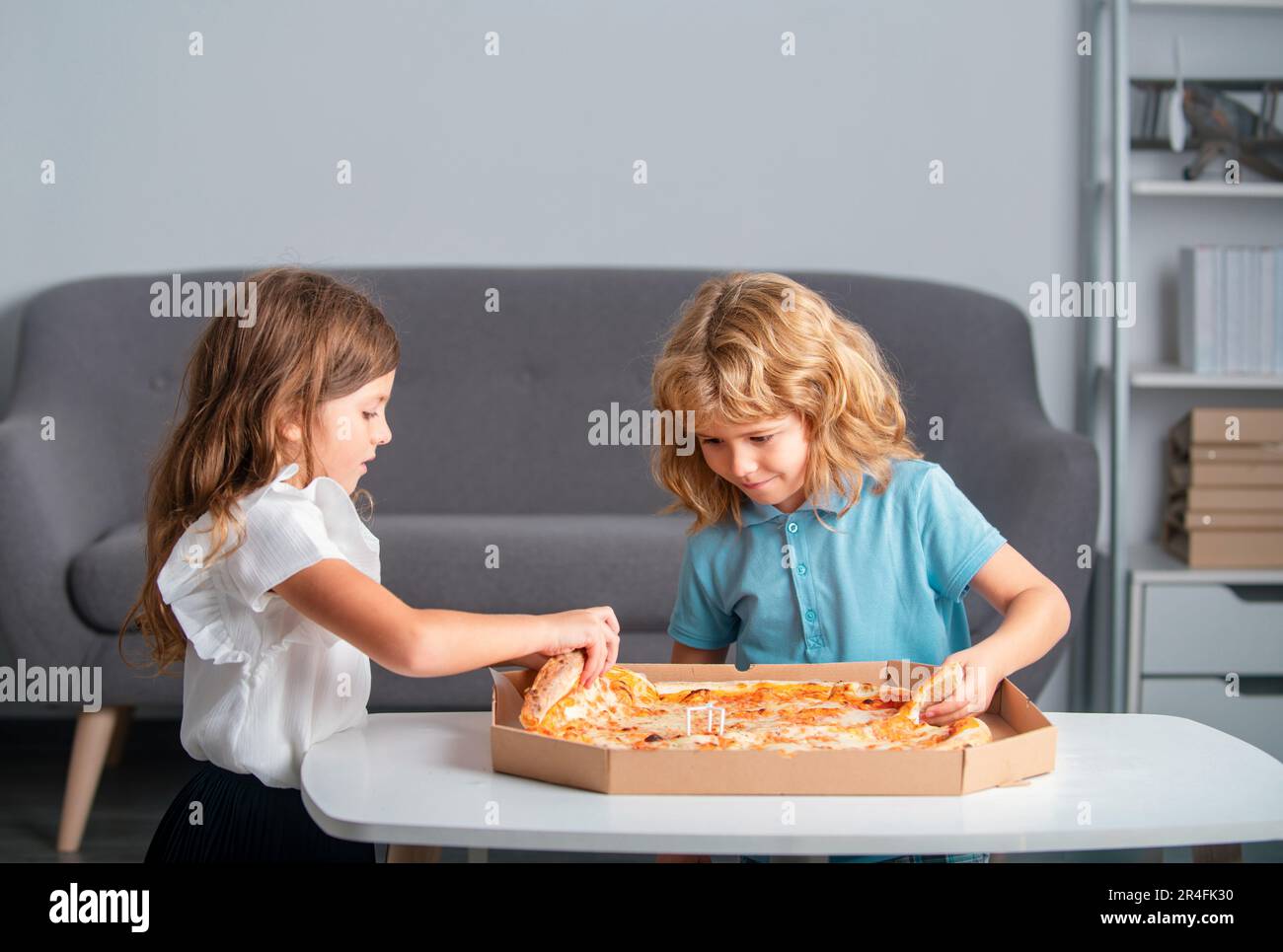 Cute little boy and girl eating Pizza at home. Children holding a ...