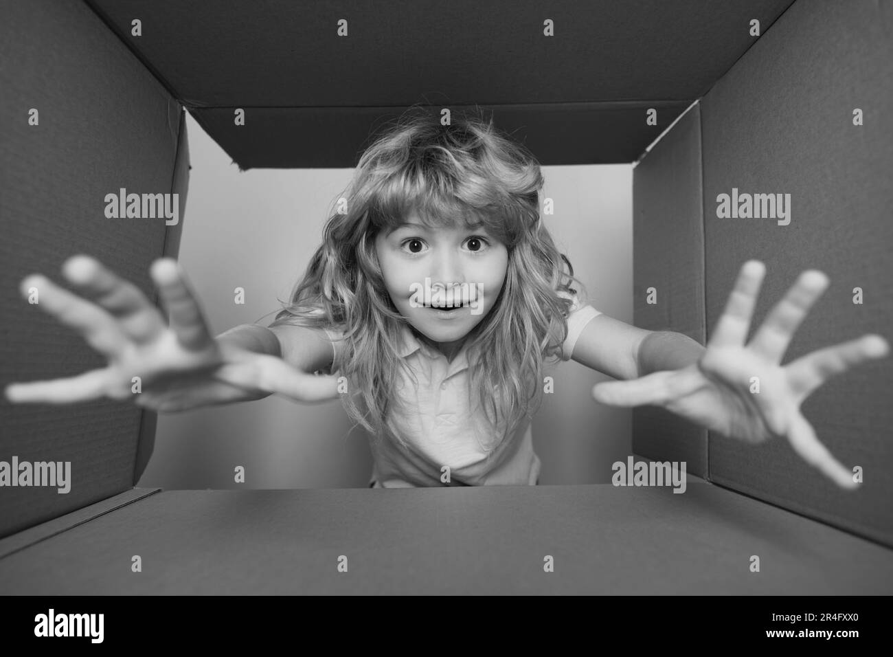 Funny child boy is opening gift and looking inside cardboard box. Child ...