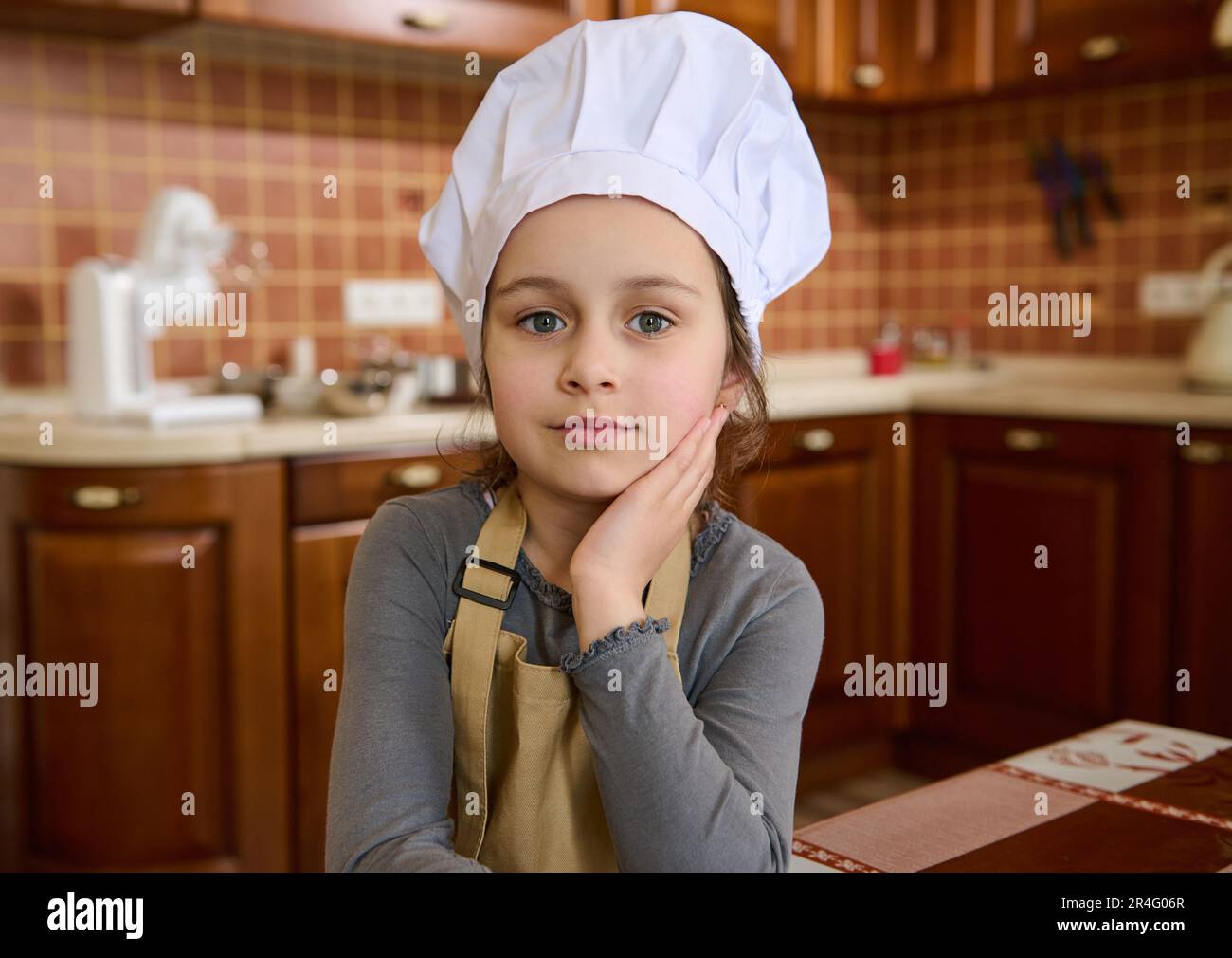 Adorable child girl in chef hat and apron, little baker confectioner ...