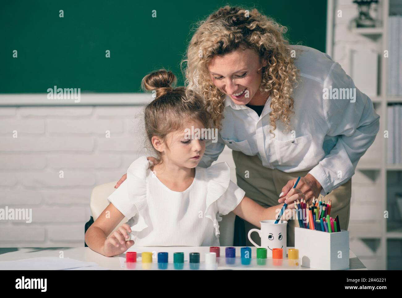 Kid drawing with teacher. Children from elementary school study at draw ...