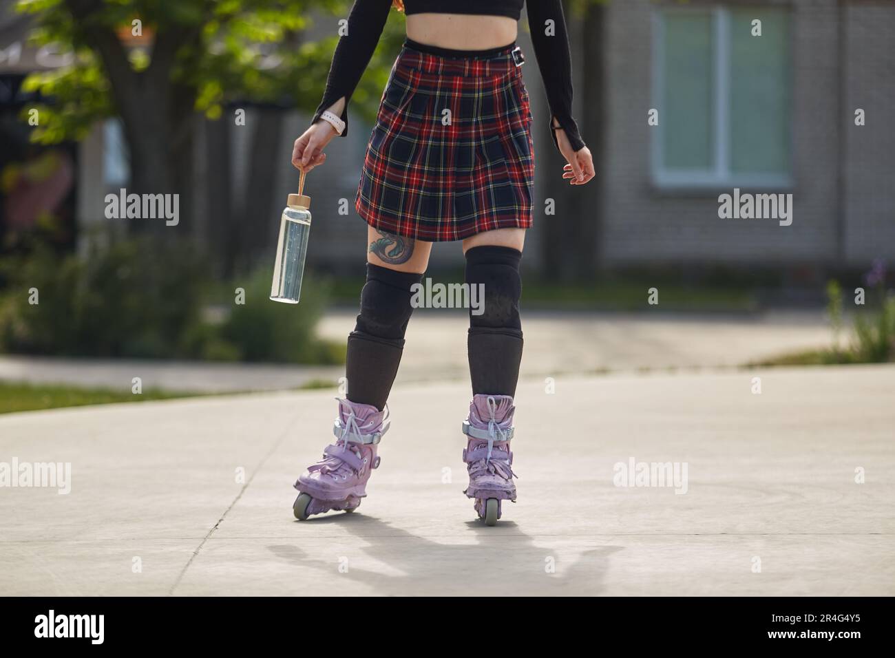 Inline skater girl roller blading in a skatepark with a glass bottle of ...