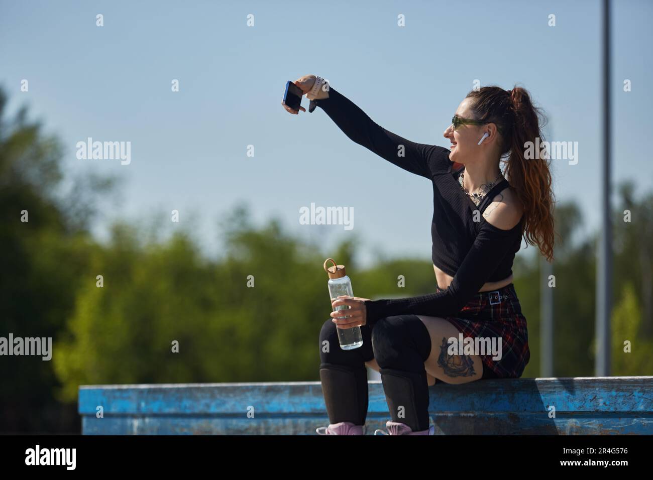 Cheerful roller blader female taking a selfie with eco glass water ...