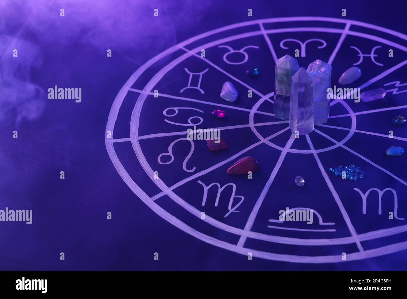 Natural stones for zodiac signs and drawn astrology chart on dark blue ...