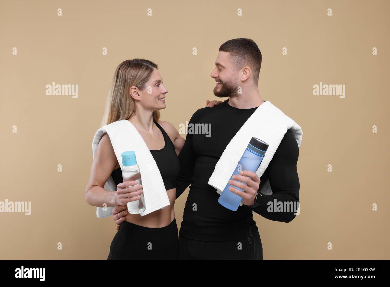 Athletic people with bottles of water and towels on light brown ...