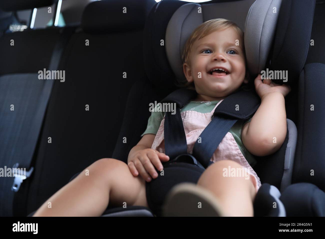 Cute little girl sitting in child safety seat inside car Stock Photo ...