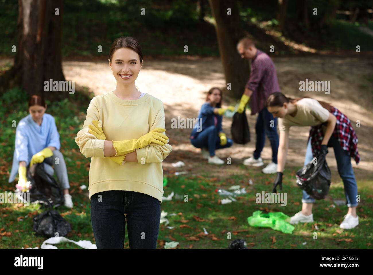 Young woman in gloves and group of people with plastic bags collecting ...