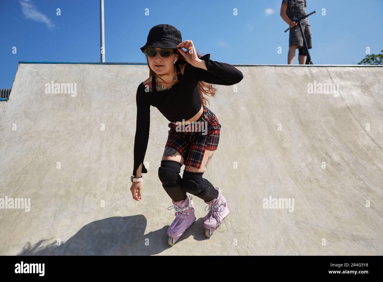 Cool young roller blader female skating in a concrete skate pool in a ...