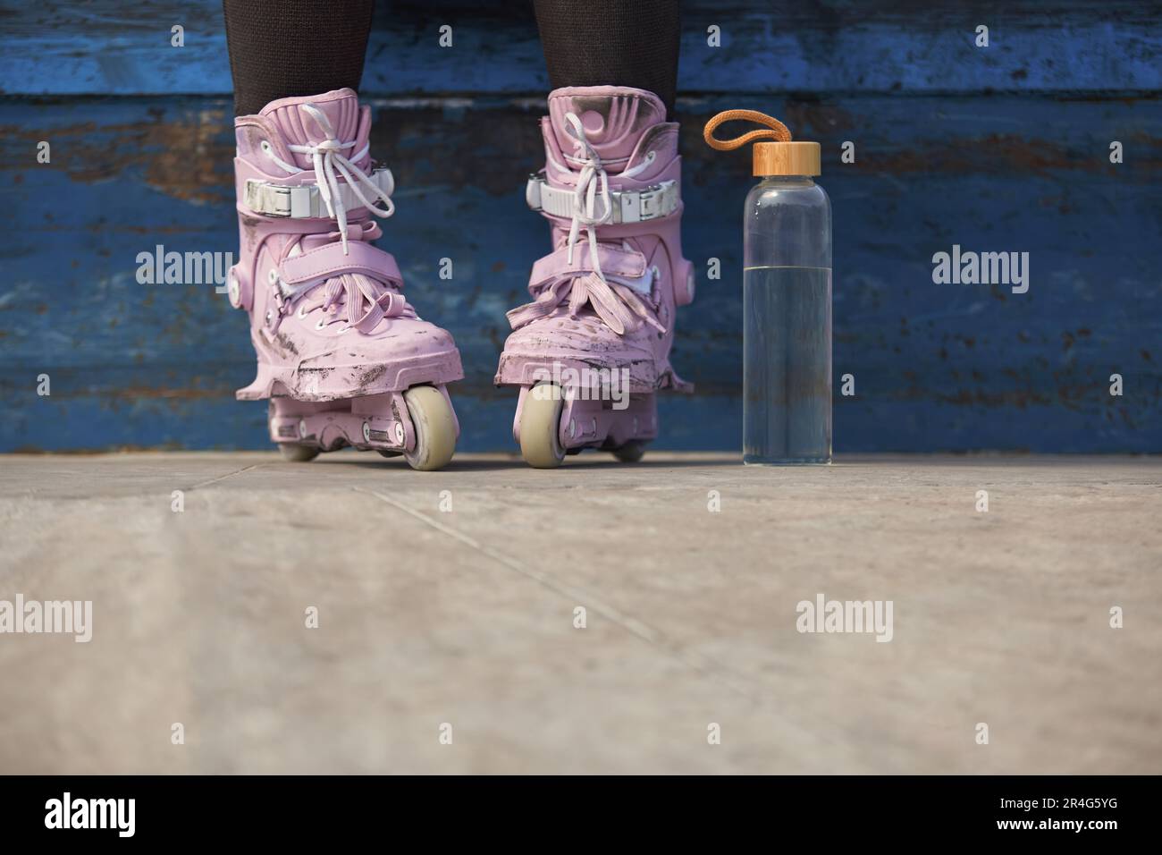 Young skater girl sitting on a ledge in a skatepark with glass water ...
