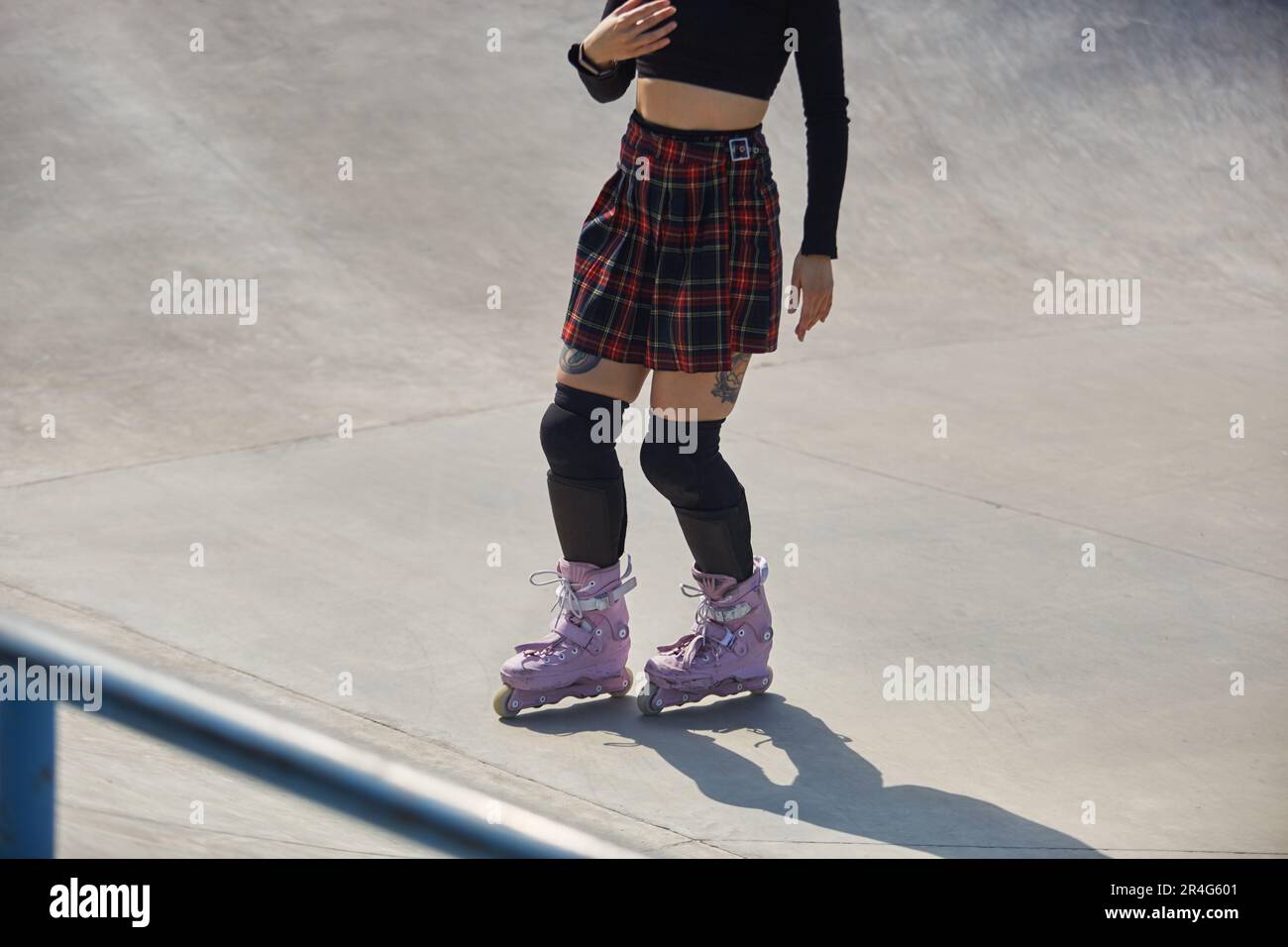 Skater girl riding on aggressive in-line skates in a concrete skatepark ...