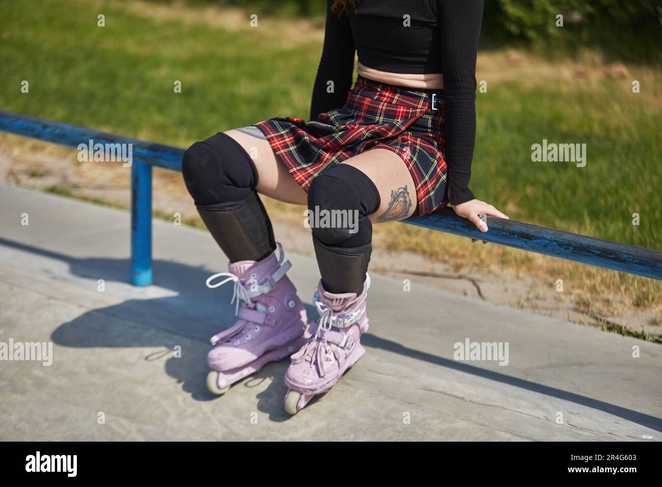 Tattooed roller blader girl sitting on a rail in a skatepark. Cool ...