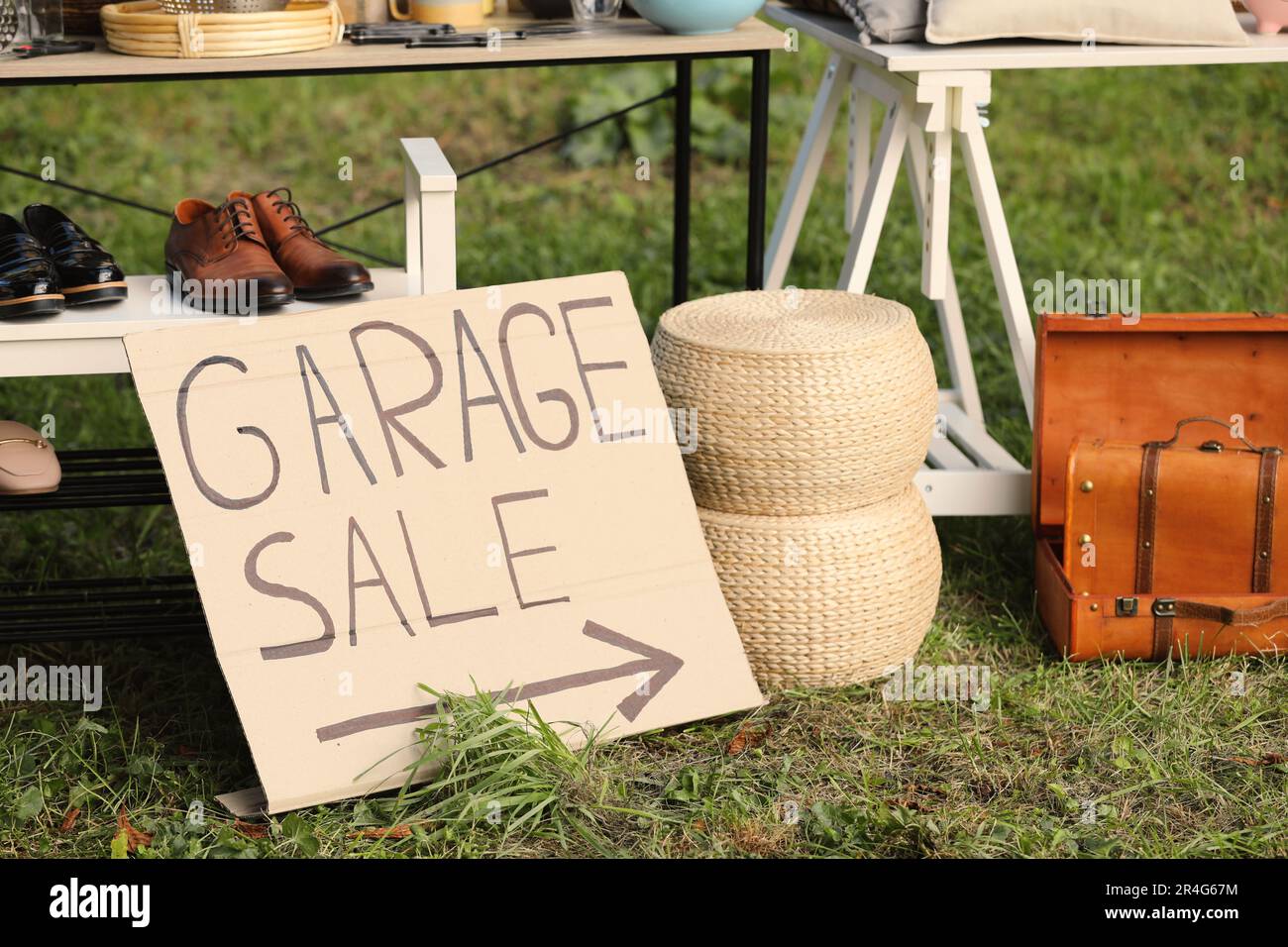 Sign Garage sale written on cardboard near tables with different stuff ...