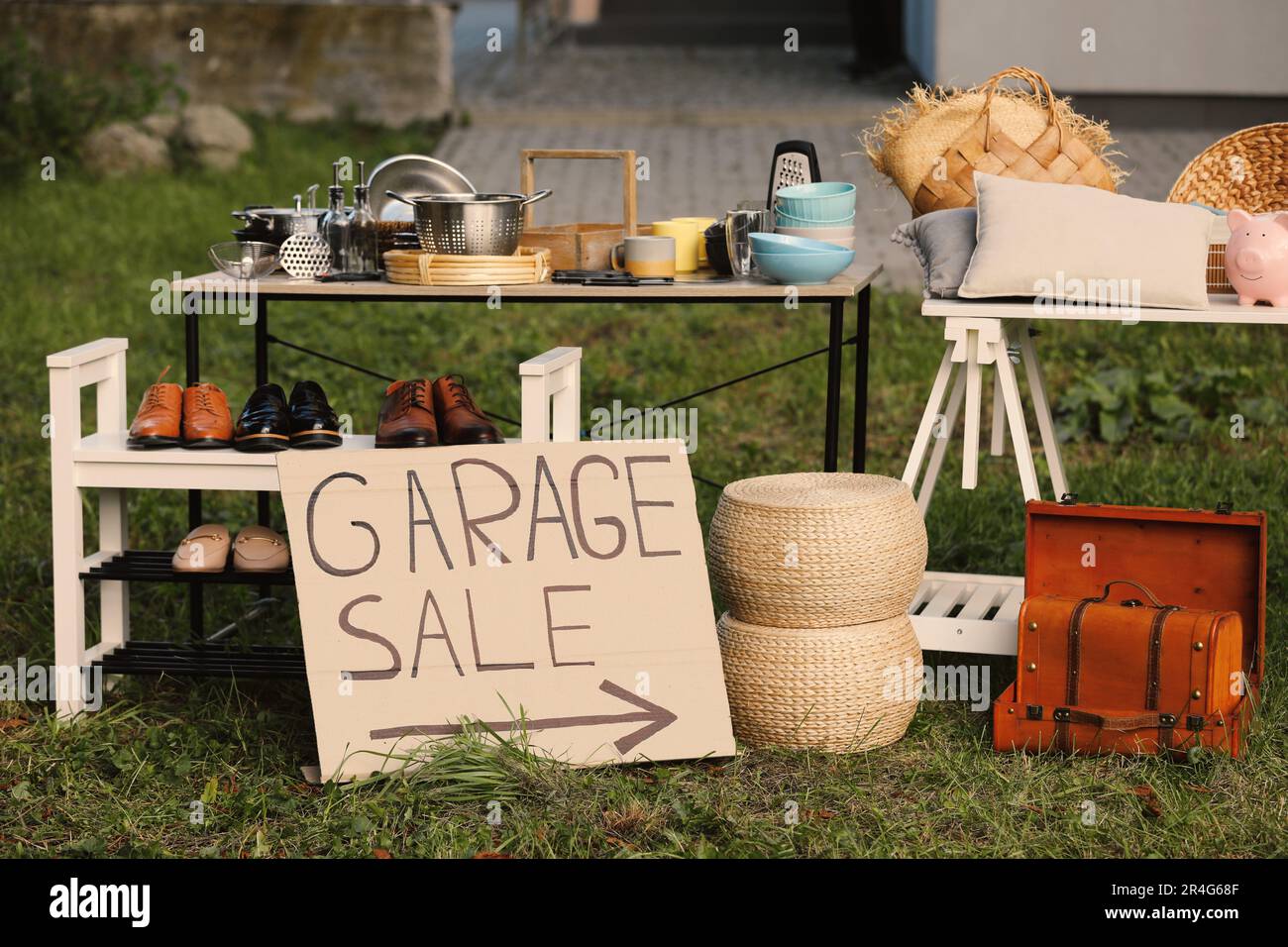 Sign Garage sale written on cardboard near tables with different stuff ...