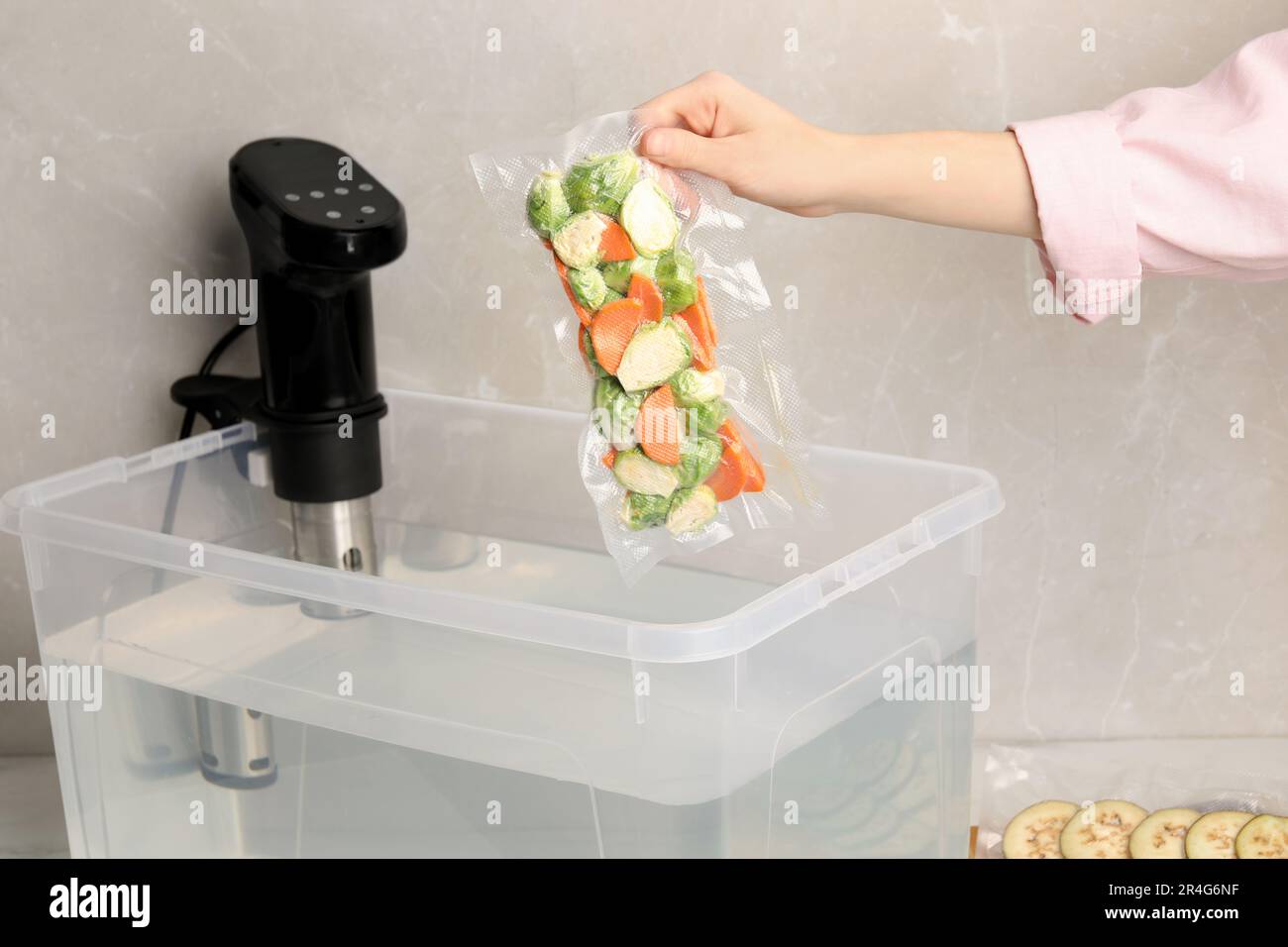 Woman putting vacuum packed vegetables into box with thermal immersion ...