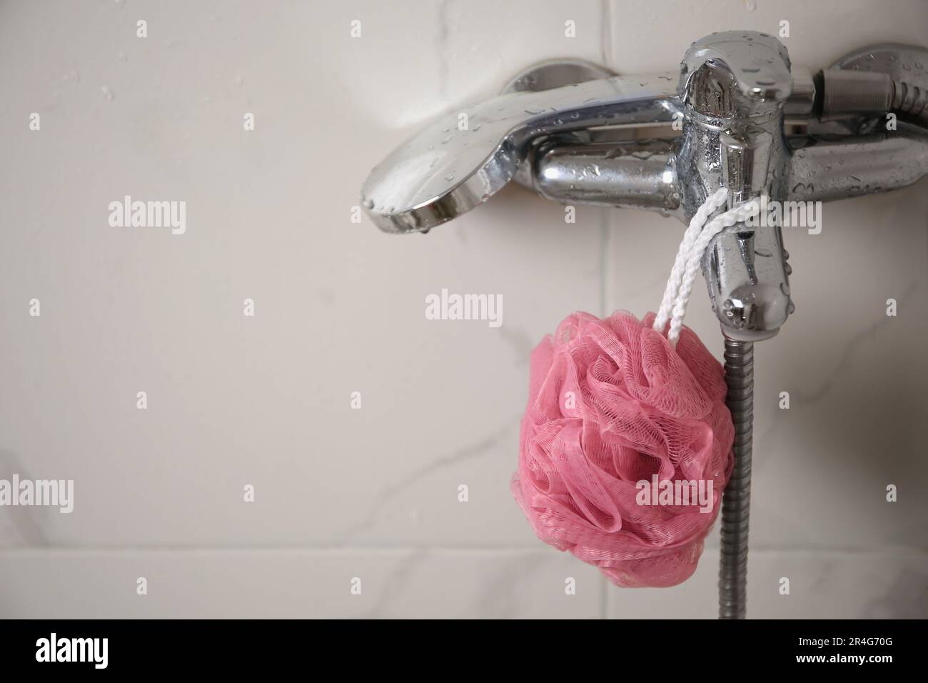 Pink shower puff hanging on faucet in bathroom, space for text Stock ...