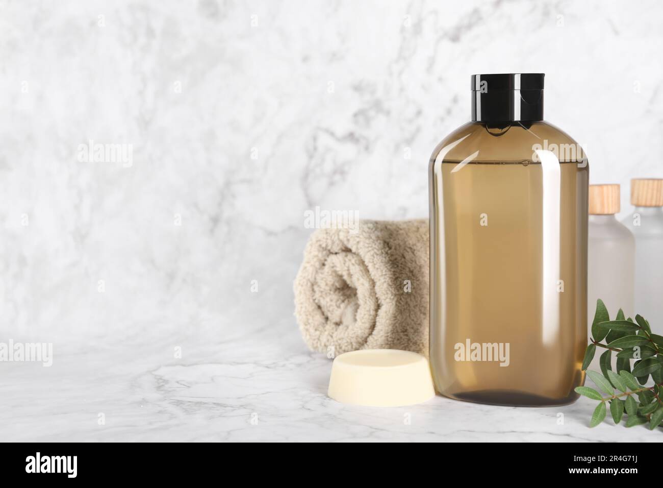 Shampoo bottle, essential oils, folded towel and solid shampoo bar on ...