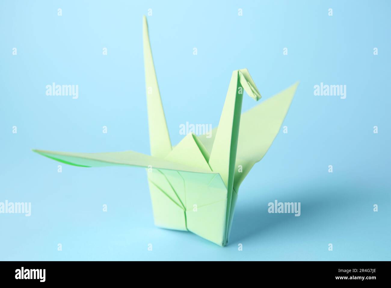 Origami art. Handmade paper crane on light blue background, closeup ...