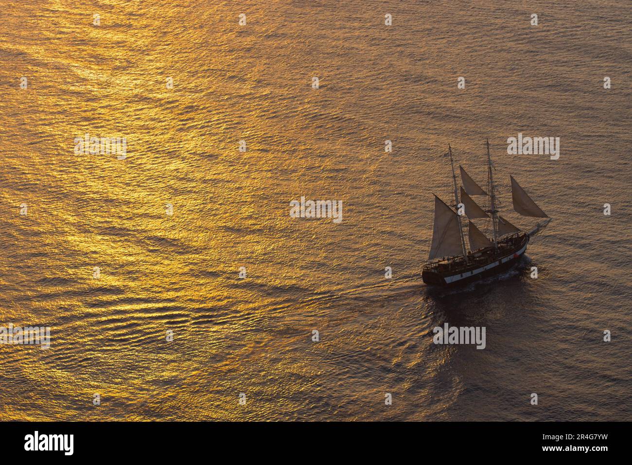 A sailing ship sails into the sunsetg Stock Photo - Alamy