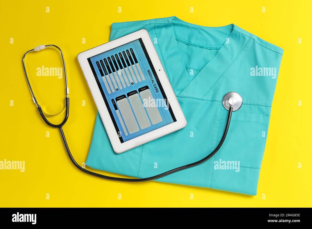 Medical uniform, tablet and stethoscope on yellow background, flat lay ...