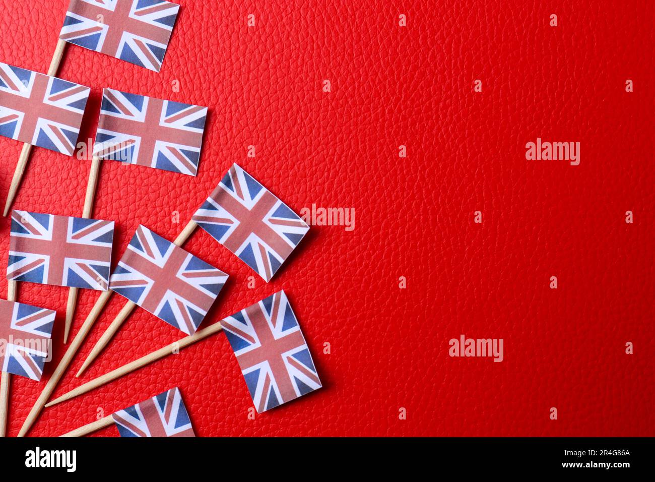 Small paper flags of United Kingdom on red textured background, flat ...